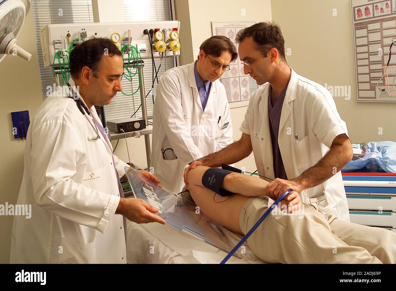 Cardiac patient. Doctors rolling a patient to insert a backboard. It is ...