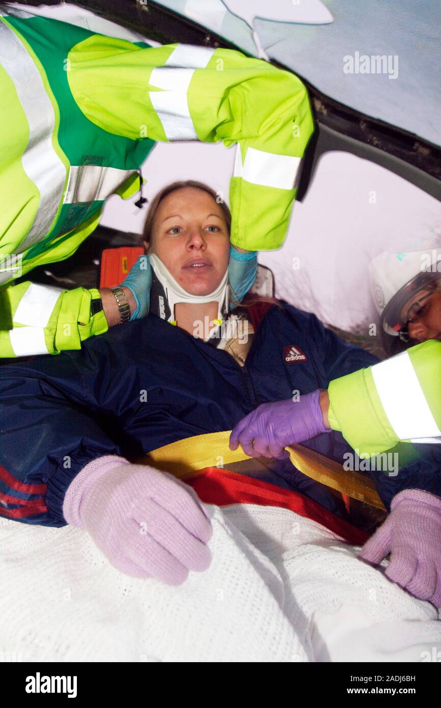 Emergency treatment. Paramedics treating a woman with a suspected neck ...