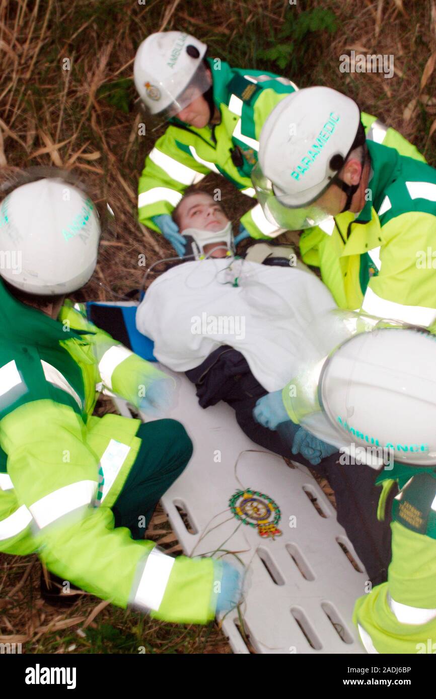 Emergency treatment. Paramedics lifting a man with a suspected neck or ...