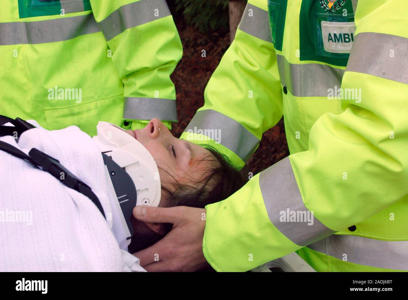 Emergency treatment. Paramedics treating a woman with a suspected neck ...