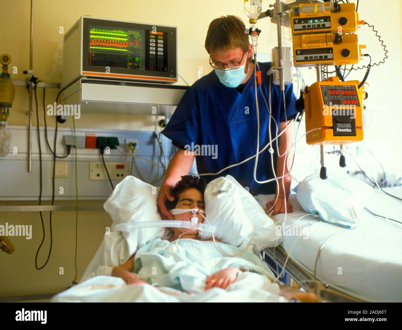Cardiac intensive care. Nurse comforting a boy who is recovering in a ...