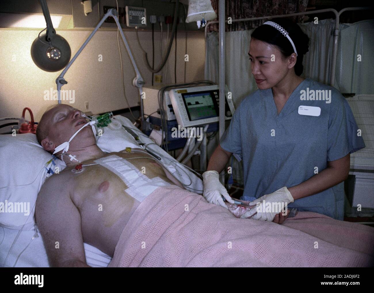 Intensive care. Nurse monitoring a patient at his bed in an intensive ...