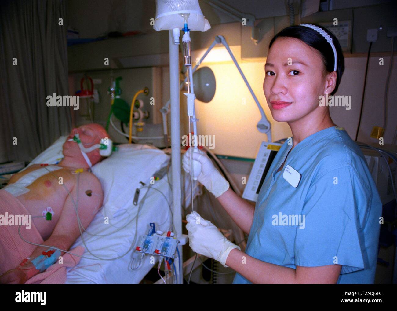 Intensive care. Nurse adjusting the rate of flow of fluid from an ...