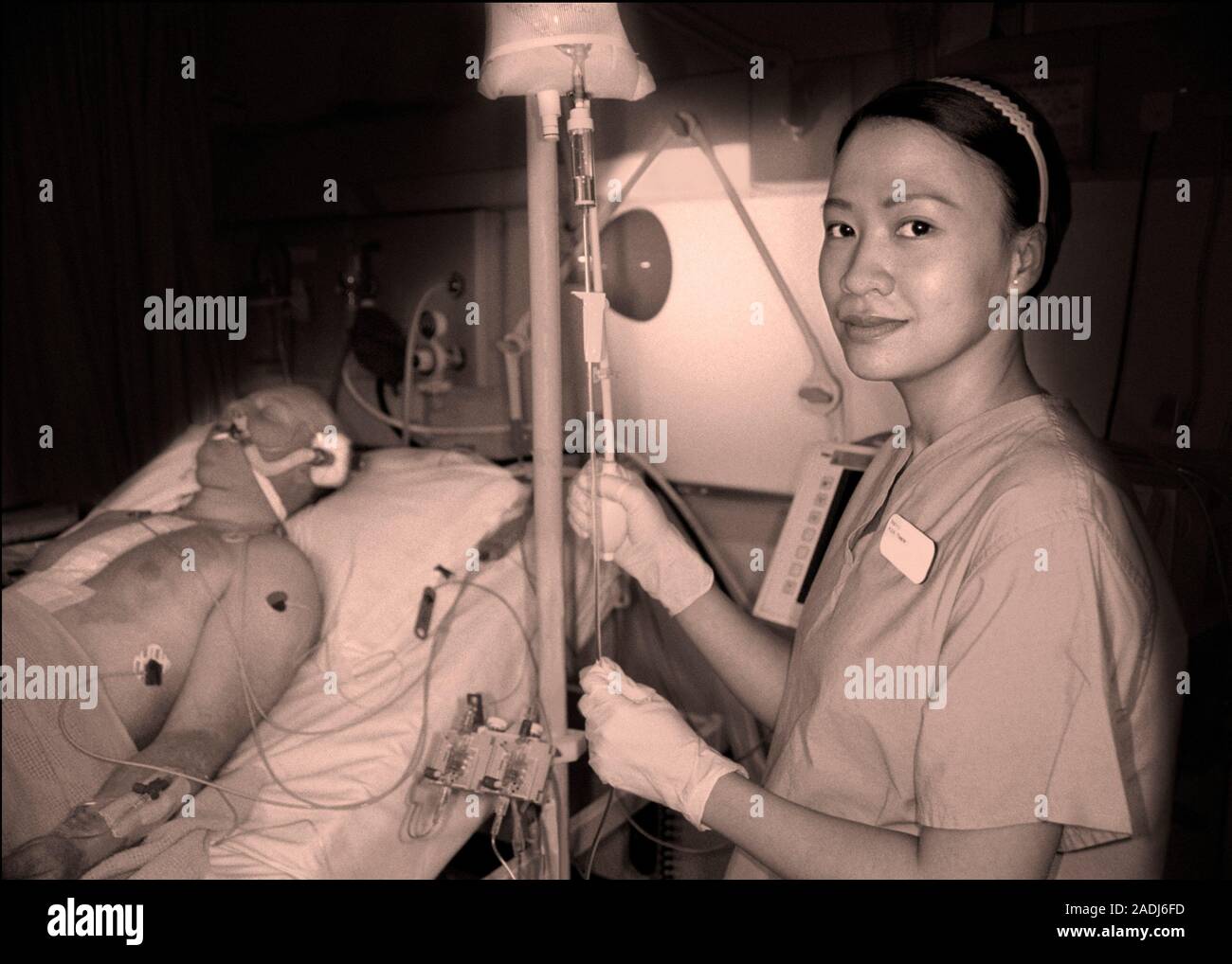 Intensive care. Nurse adjusting the rate of flow of fluid from an ...