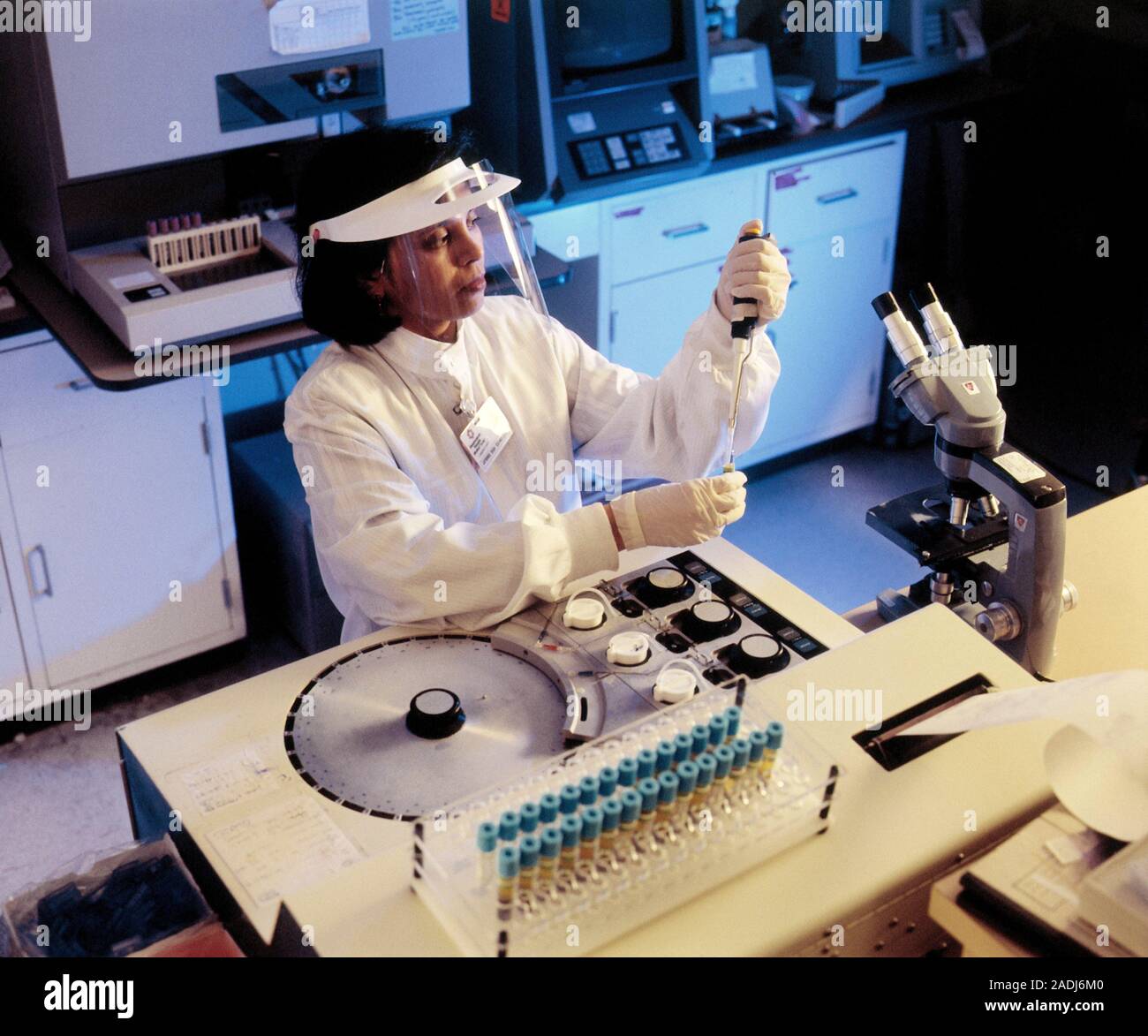 Blood centrifuge. Masked female technician pipetting a blood sample ...