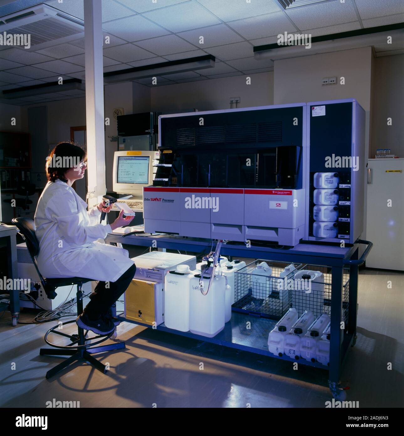 Blood analysis. Female researcher placing a multi-well sample tray ...