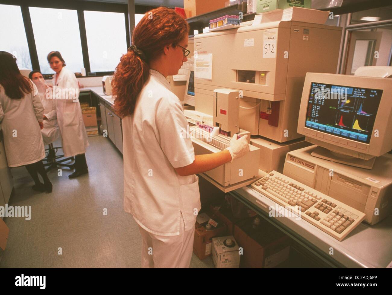 Blood sample analysis. Technician overseeing the automated clinical ...