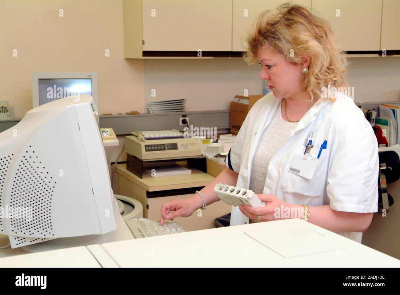 Blood testing. Medical laboratory worker using a computer to find the ...
