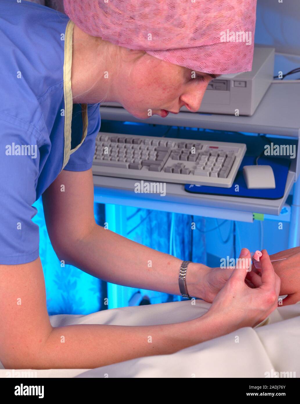 Inserting cannula. A nurse inserts a Venflon cannula into a vein on the ...