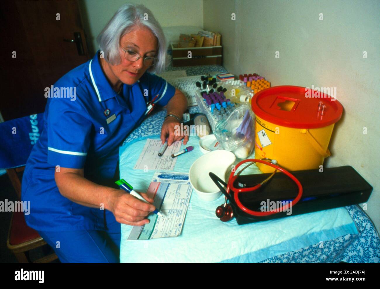 Blood sampling paperwork. Female nurse writing out paperwork for blood ...