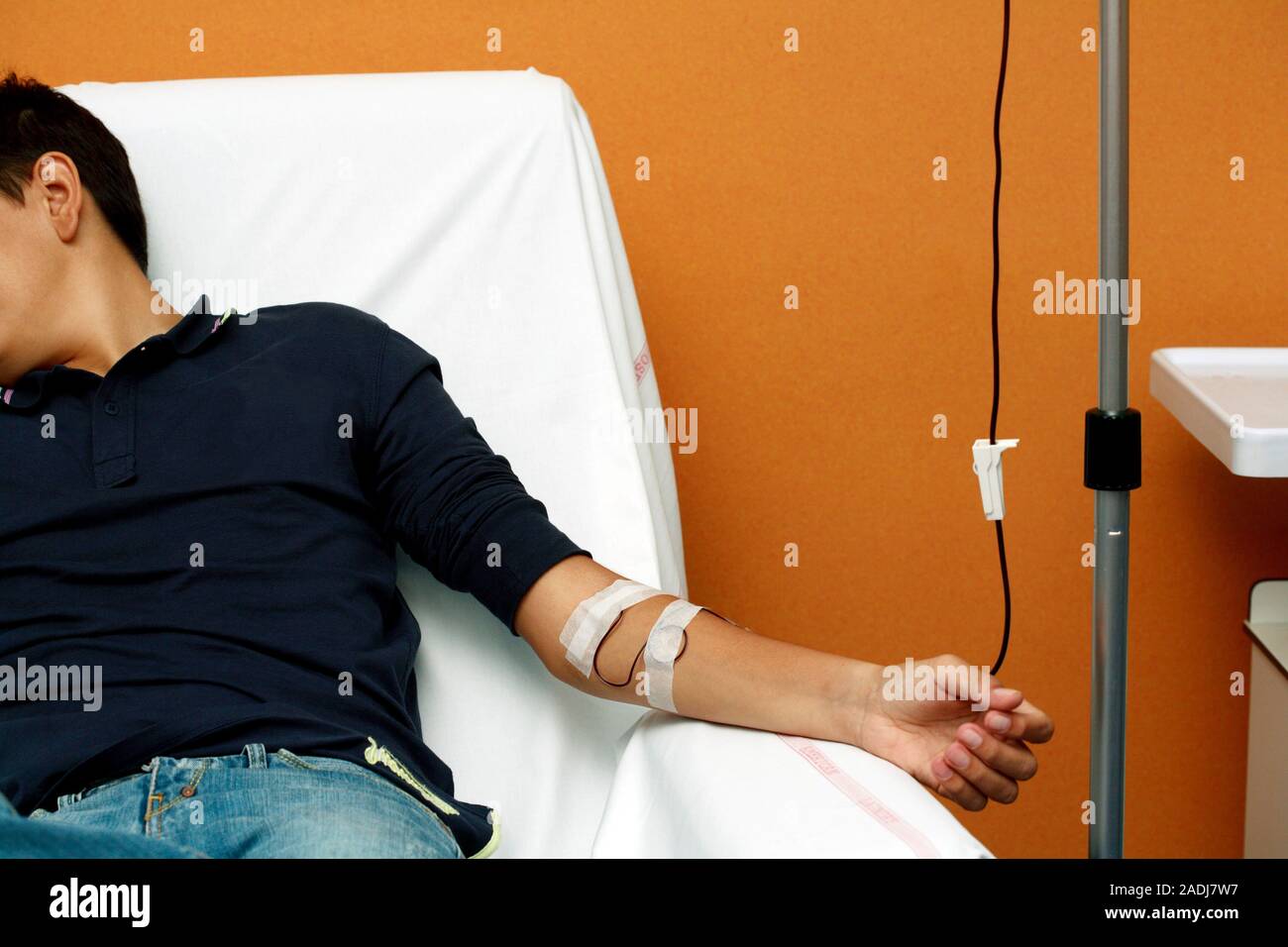 Blood transfusion. Blood-filled tubing attached to a patient's arm ...