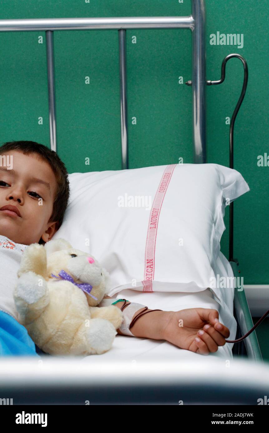 Paediatric blood transfusion. Young boy with blood-filled tubing ...