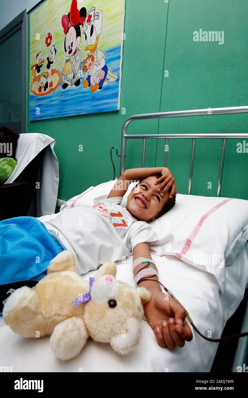 Paediatric blood transfusion. Smiling young boy with blood-filled ...