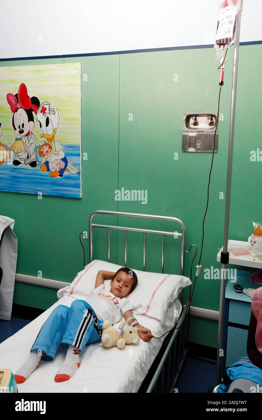 Paediatric blood transfusion. Young boy with blood-filled tubing ...