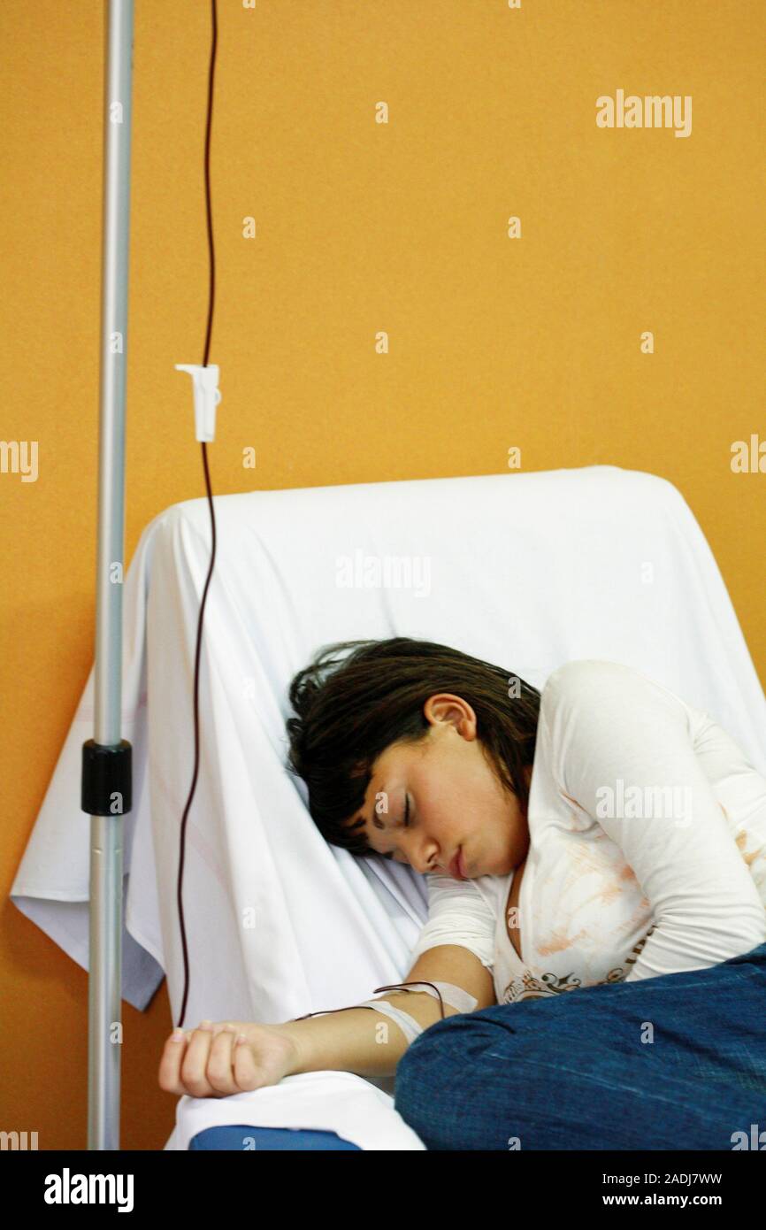 Paediatric blood transfusion. Teenage girl with blood-filled tubing ...
