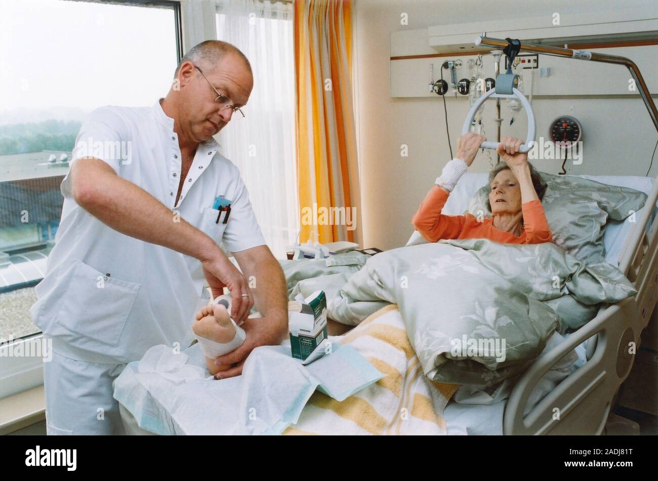 Terminal care. Hospital nurse bandaging a terminally ill patient's foot ...