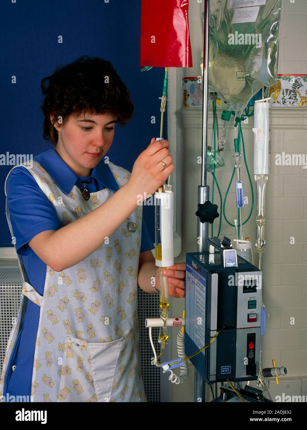 Paediatric nurse adjusting an infusion pump, a type of automated drip ...