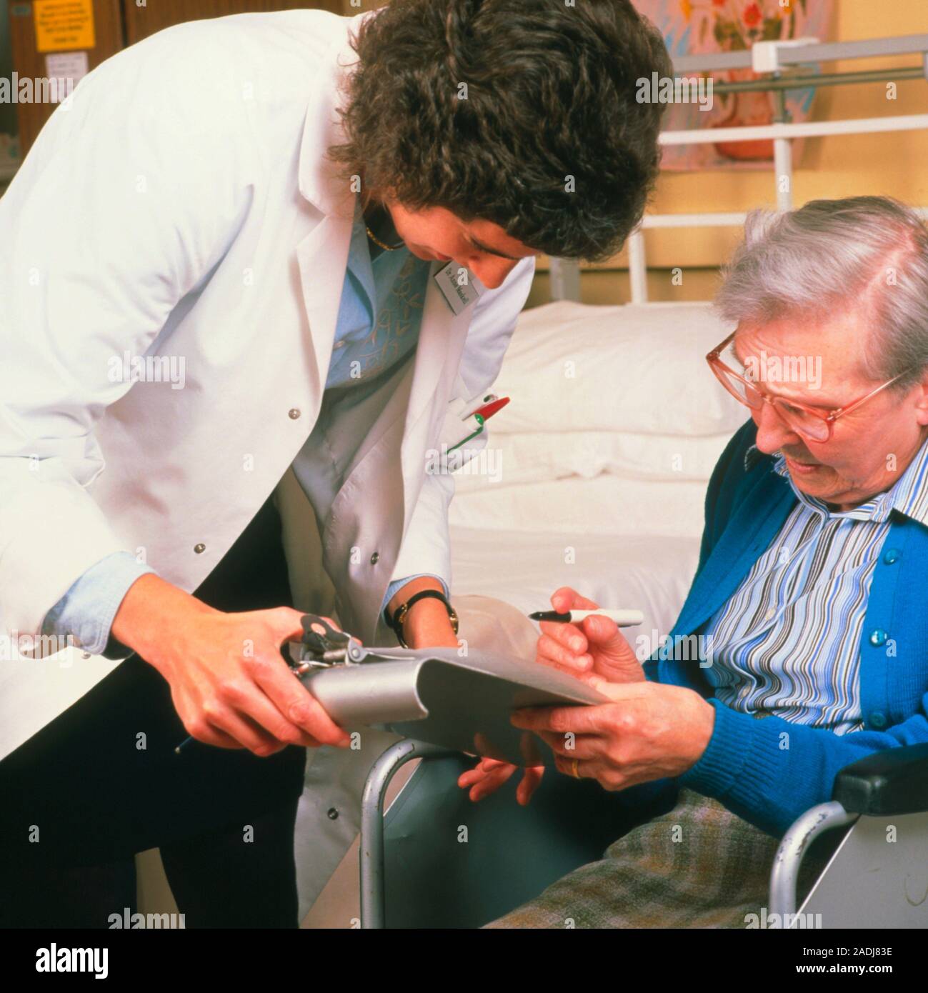 A woman patient seen in a hospital ward signing a consent form for a ...
