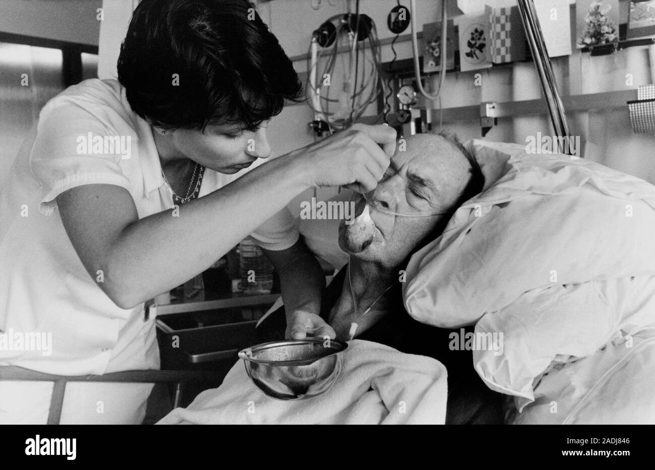 Patient being spoon-fed. A nurse spoon-feeds a very sick man in a ...