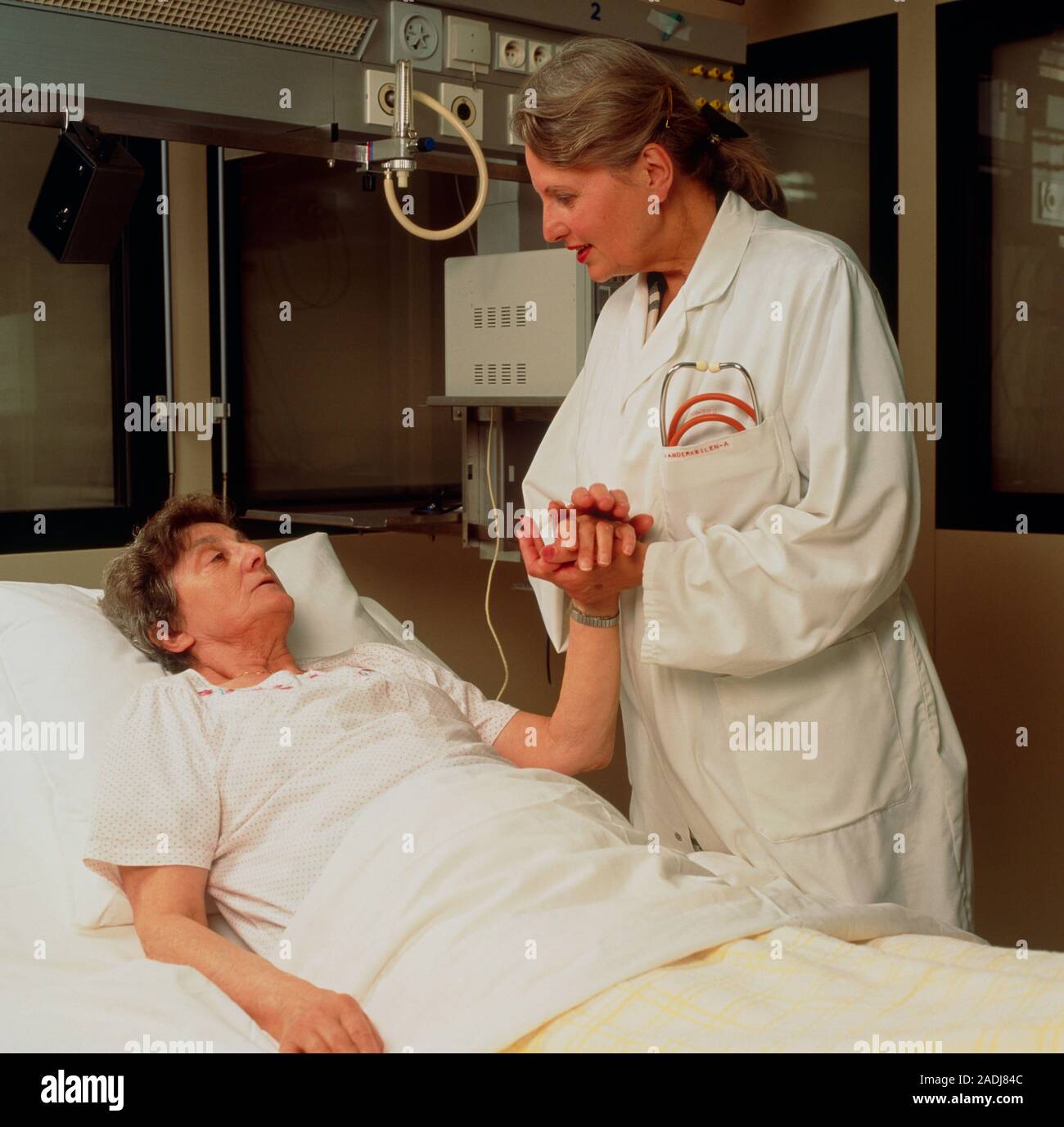 Geriatric care. Doctor attends an elderly woman in bed in the ward of a ...