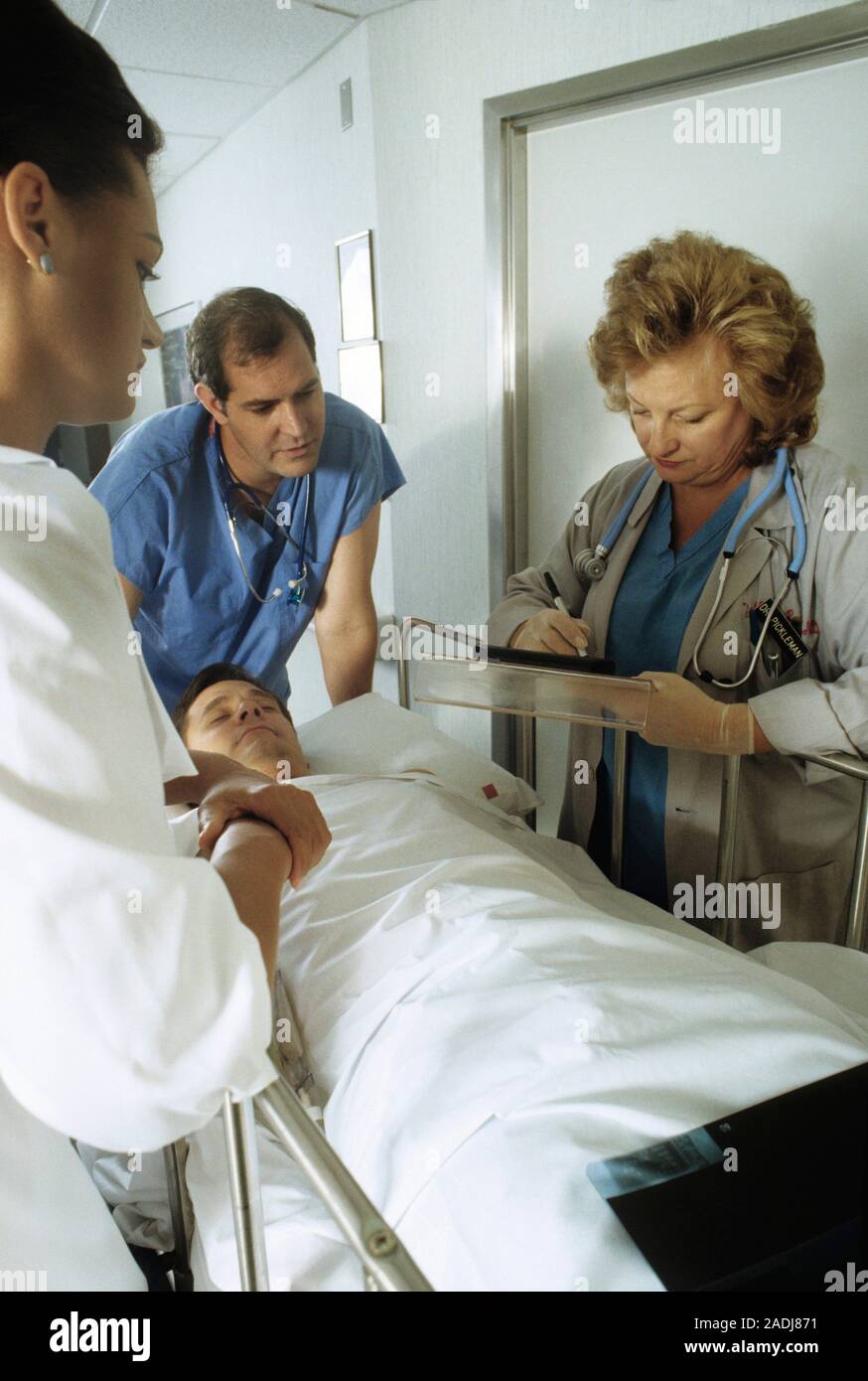 Transfer to ward. View of a female doctor (centre right) supervising ...