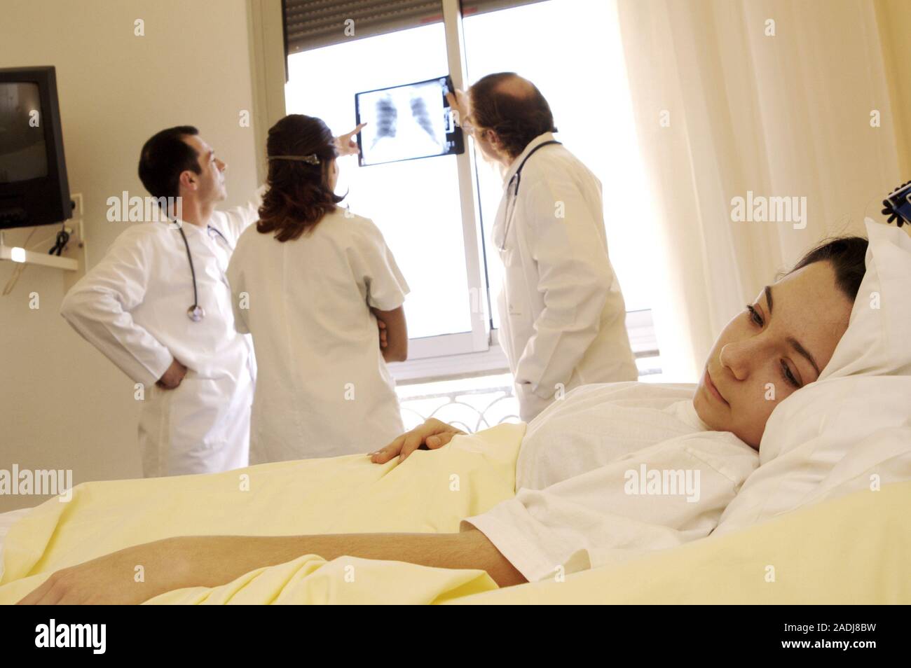 Doctors and patient. Doctors examining a patient's X-ray by holding it ...