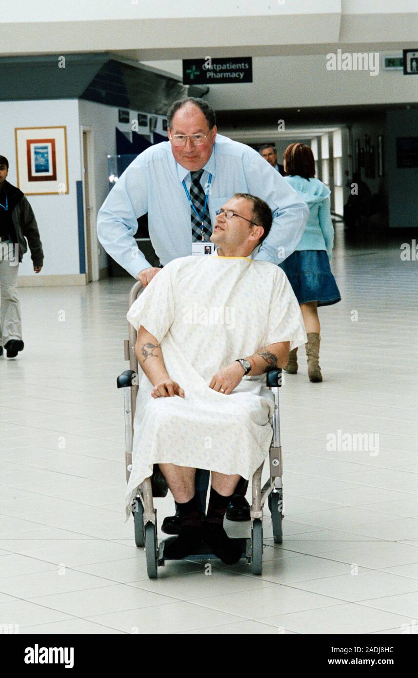 MODEL RELEASED. Hospital porter pushing a patient in a wheelchair Stock ...