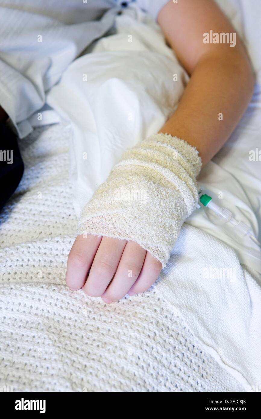 MODEL RELEASED. Intravenous drip. Child patient with a bandaged arm ...