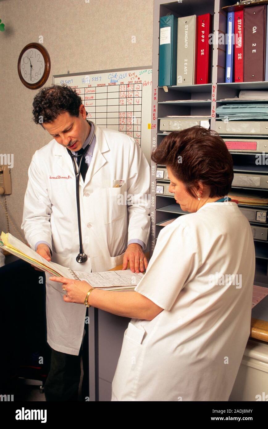 MODEL RELEASED. Medical workstation. Doctor and nurse confer over a ...