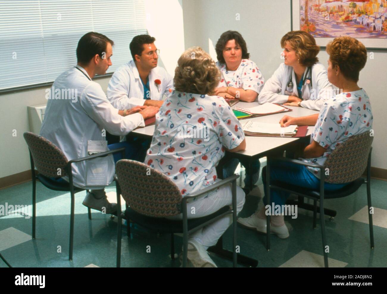 Hospital staff conference. Hospital doctors and nurses sit around a ...