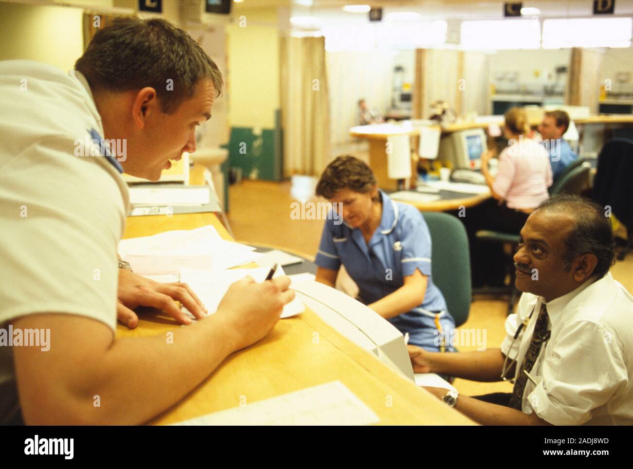 Hospital doctor and nurse talking at a workstation in an accident and ...