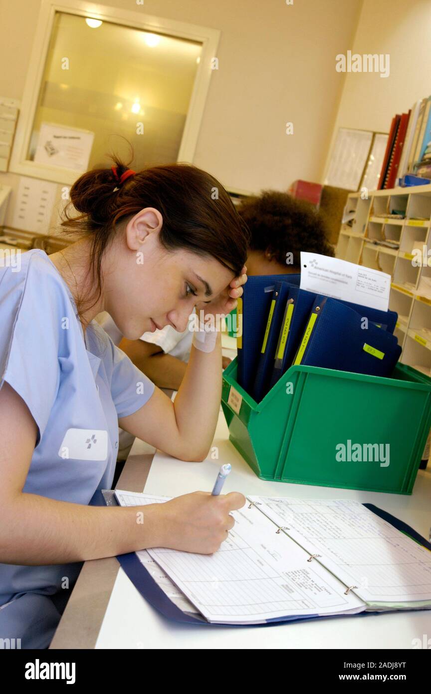 Hospital nurse doing paperwork. She has a plaster on her left wrist ...