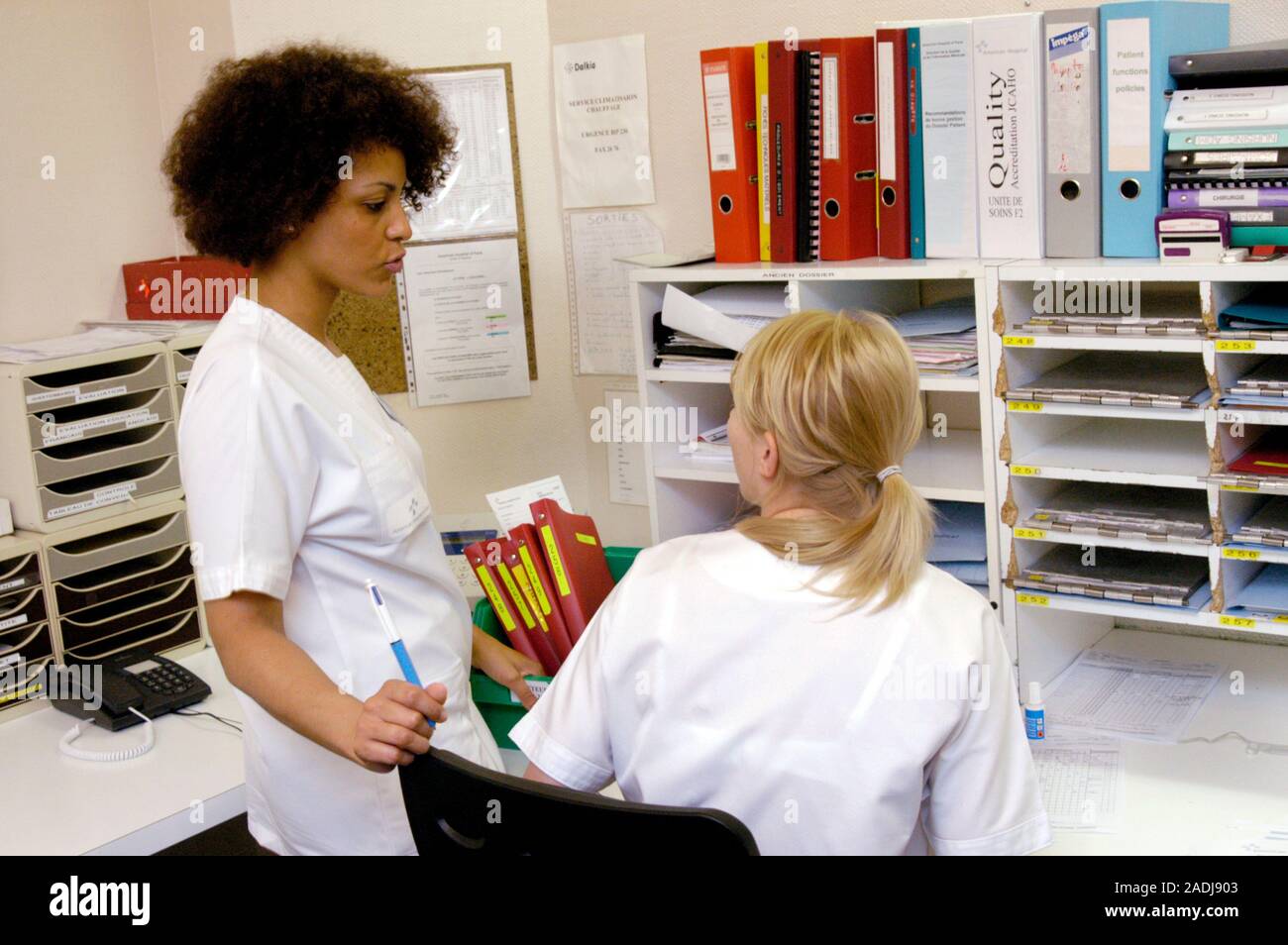 Hospital nurses talking at their workstation. Photographed at the ...