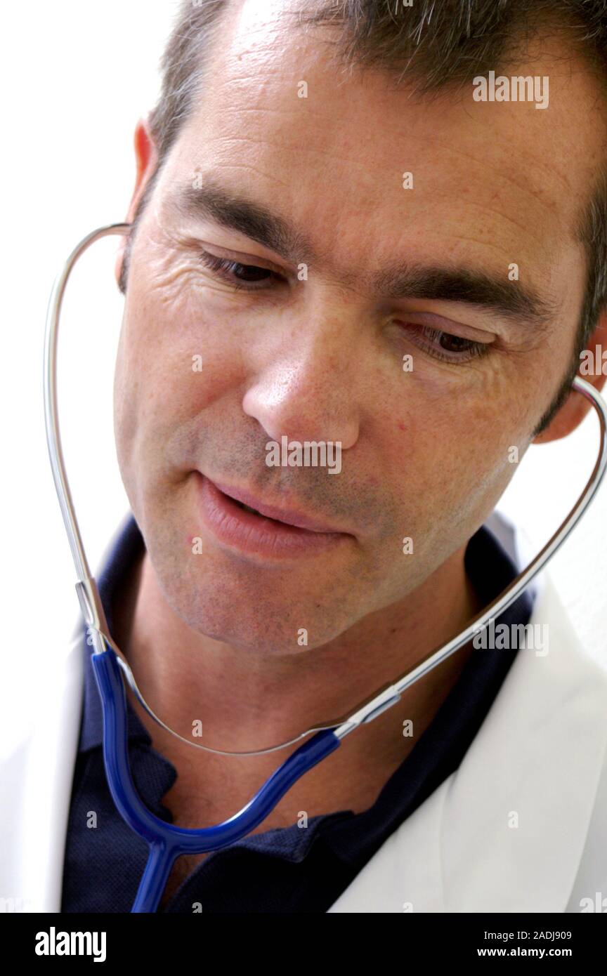 Hospital doctor with the earpieces of a stethoscope in his ears. The ...