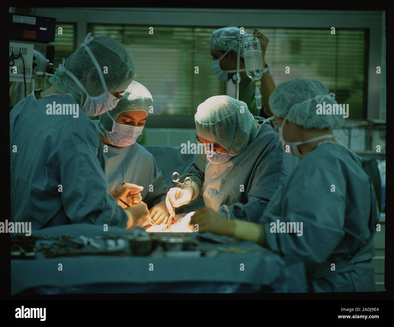 Surgeons. A masked surgery team operates on a patient in a hospital ...