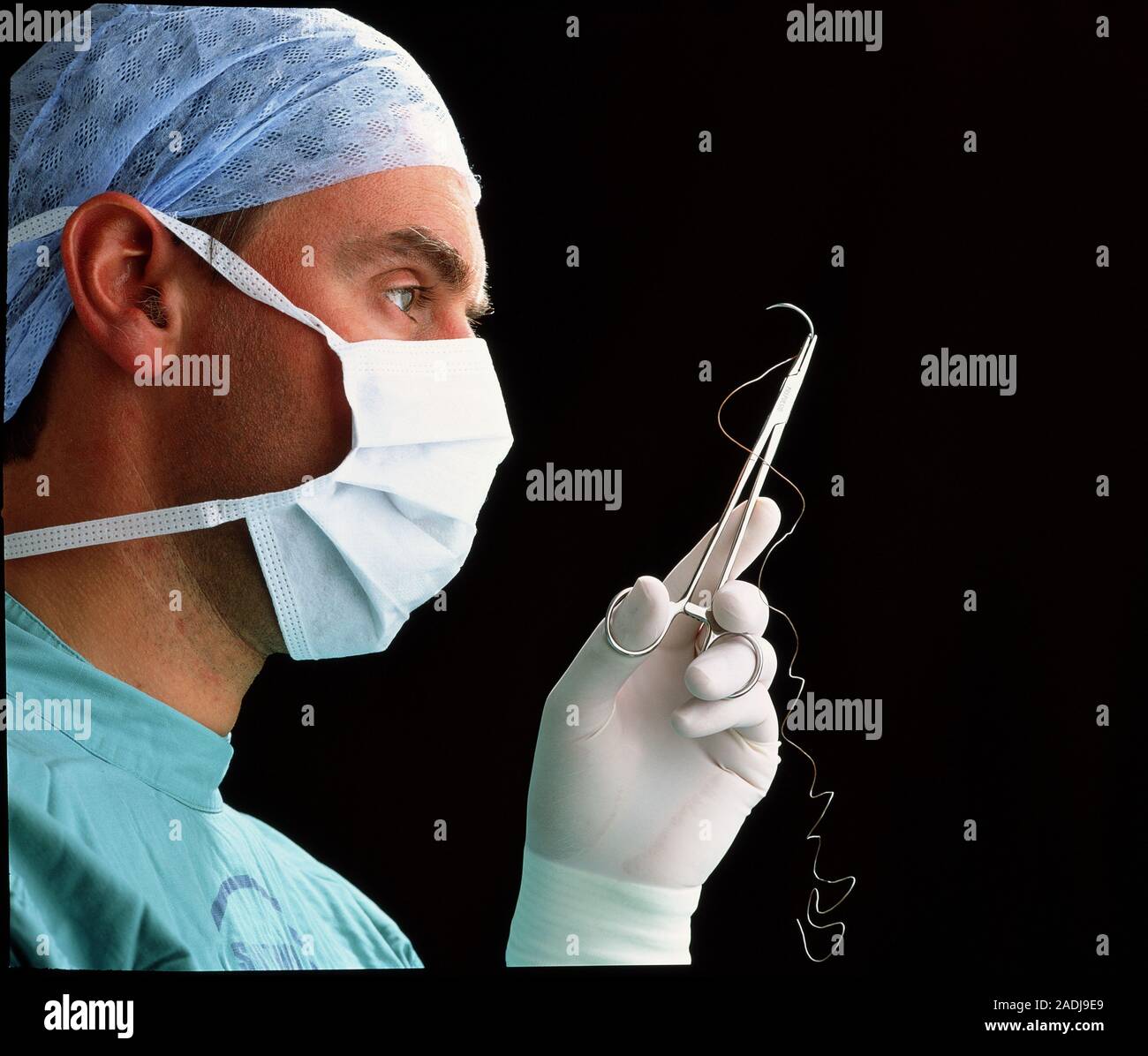 Surgeon with suture. Profile of the face of a masked surgeon holding a ...
