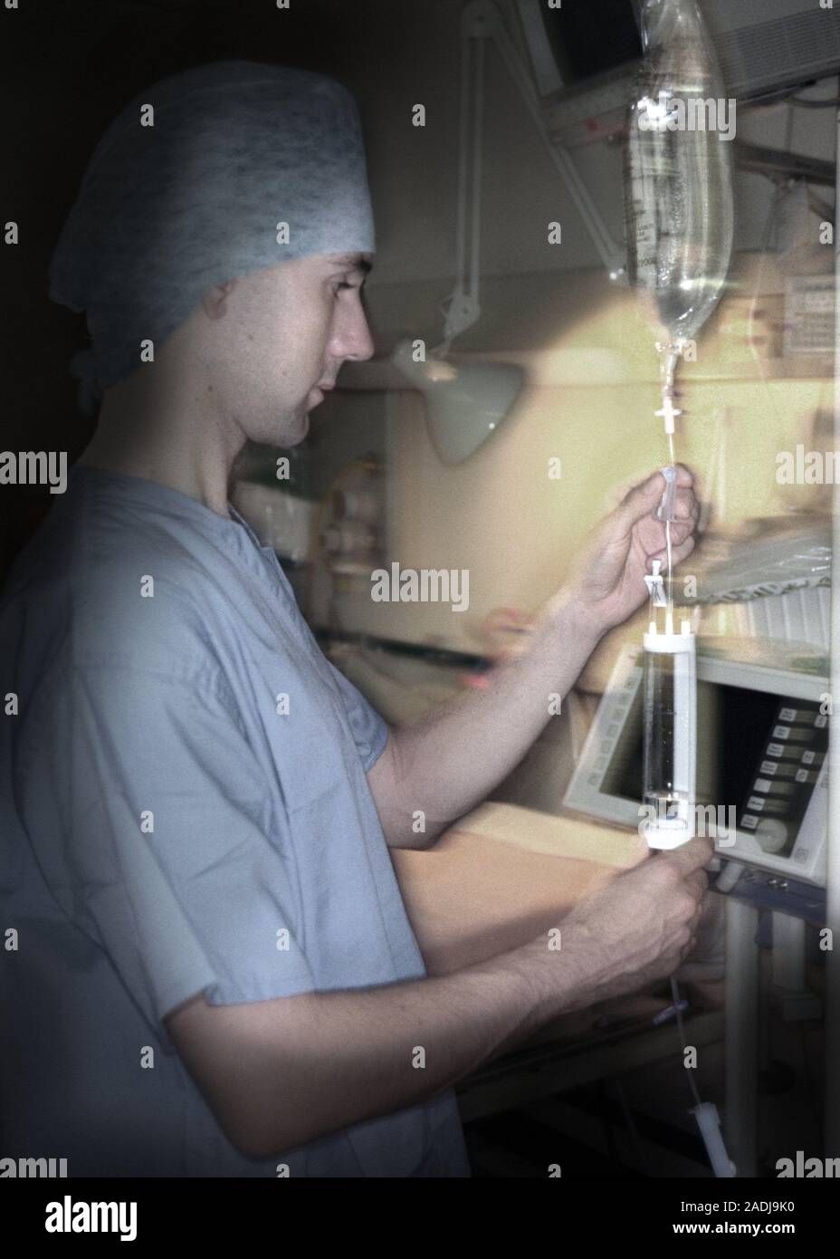 Theatre nurse adjusting the rate of flow of fluid from an intravenous ...