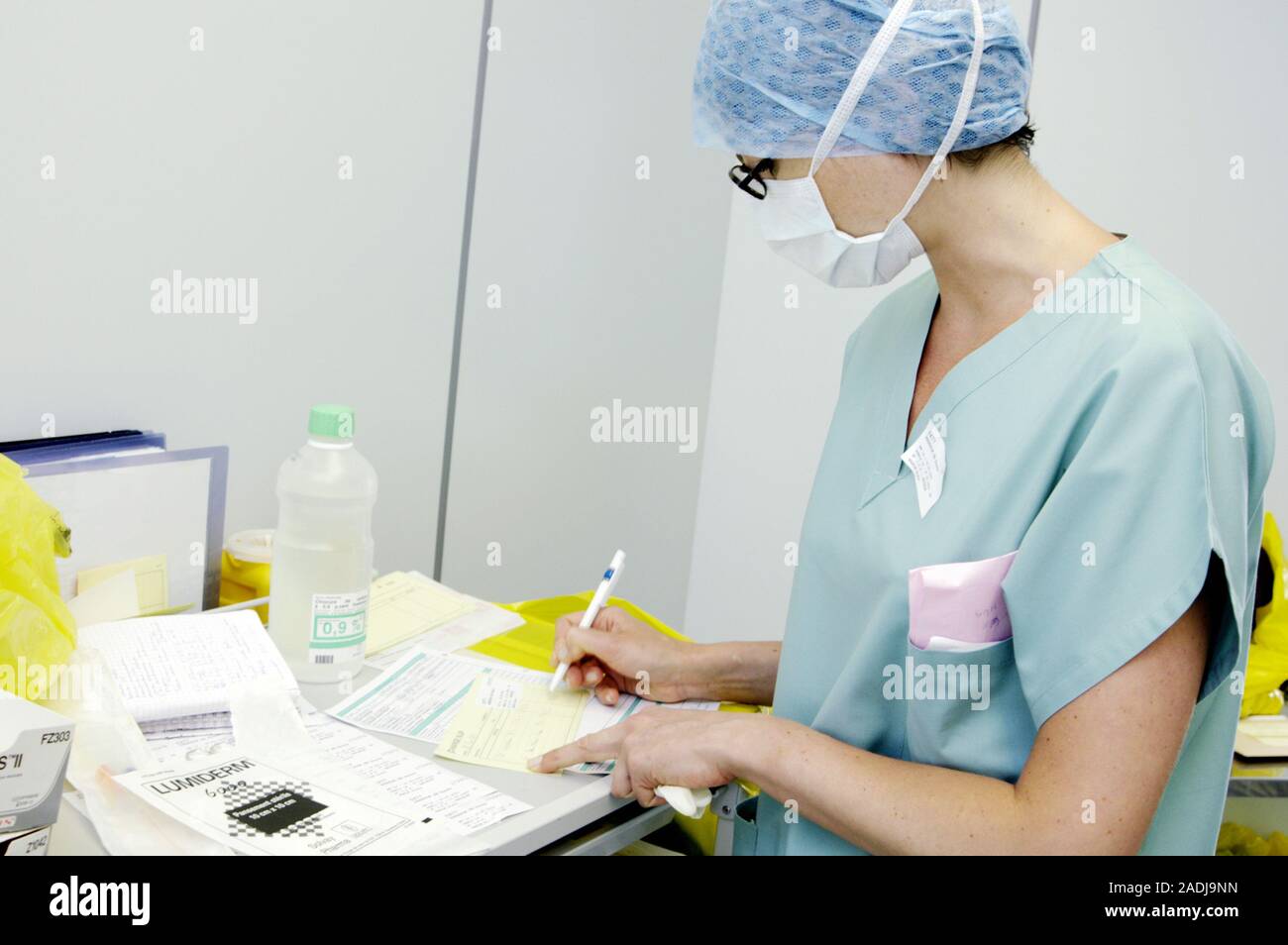 Nurse taking notes in an operating theatre, listing material used ...