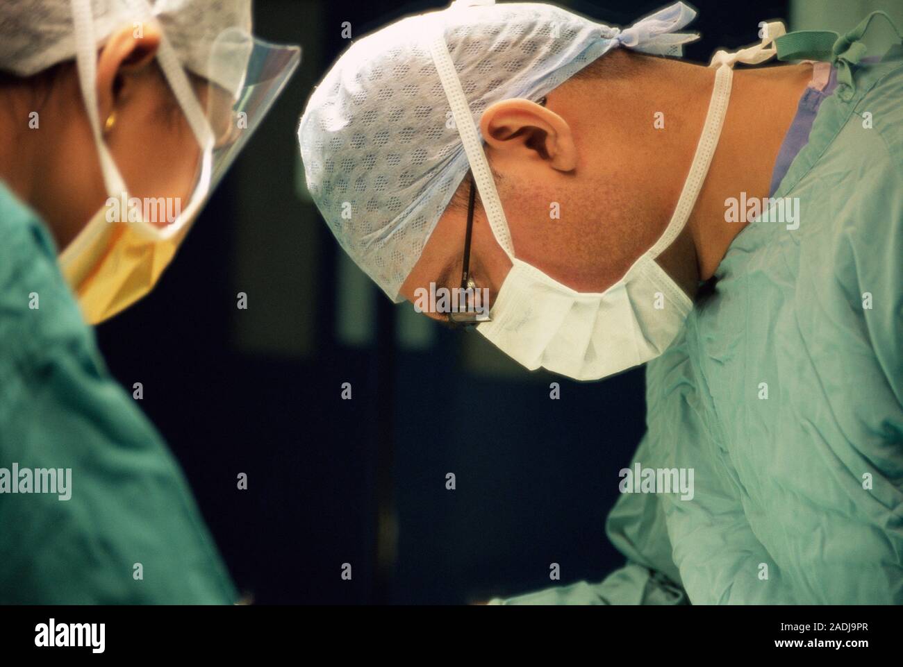 Hospital surgeon carrying out an operation. He is wearing a face mask ...