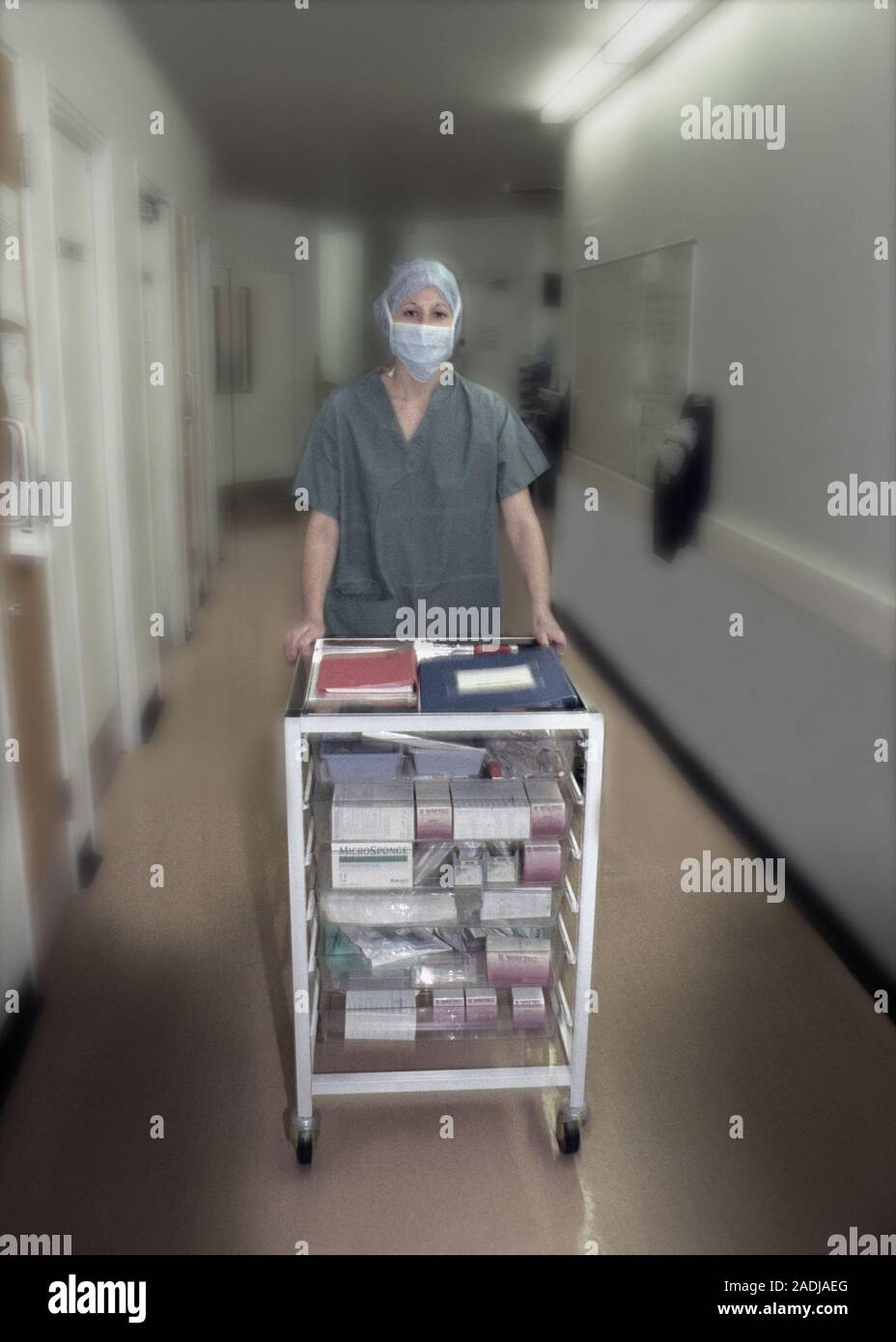 Surgical supplies. Theatre nurse wheeling a trolley loaded with ...