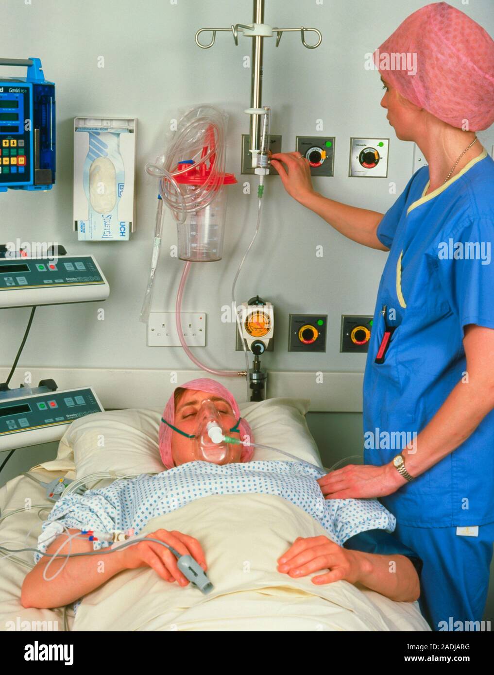 MODEL RELEASED. Post-operative recovery. A woman lies unconscious in a ...