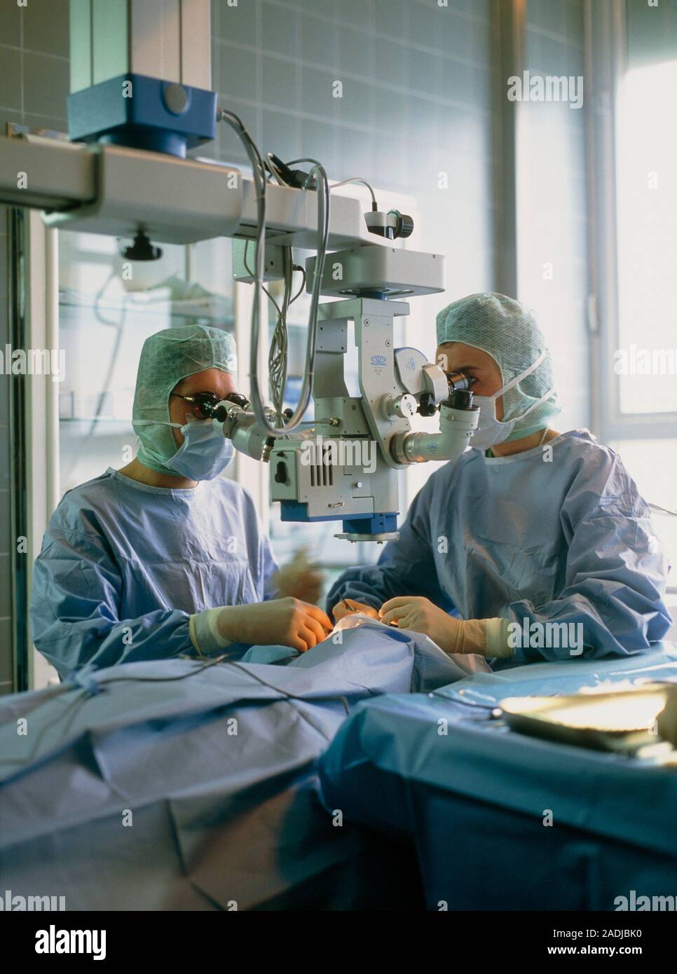 Eye microsurgery. Surgeons look through a microscope suspended over a ...