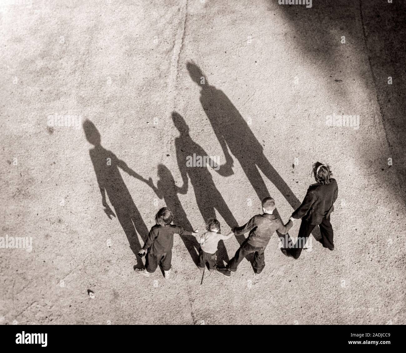 1950s OVERHEAD OF ANONYMOUS FAMILY OF 4 STANDING HOLDING HANDS CASTING ...