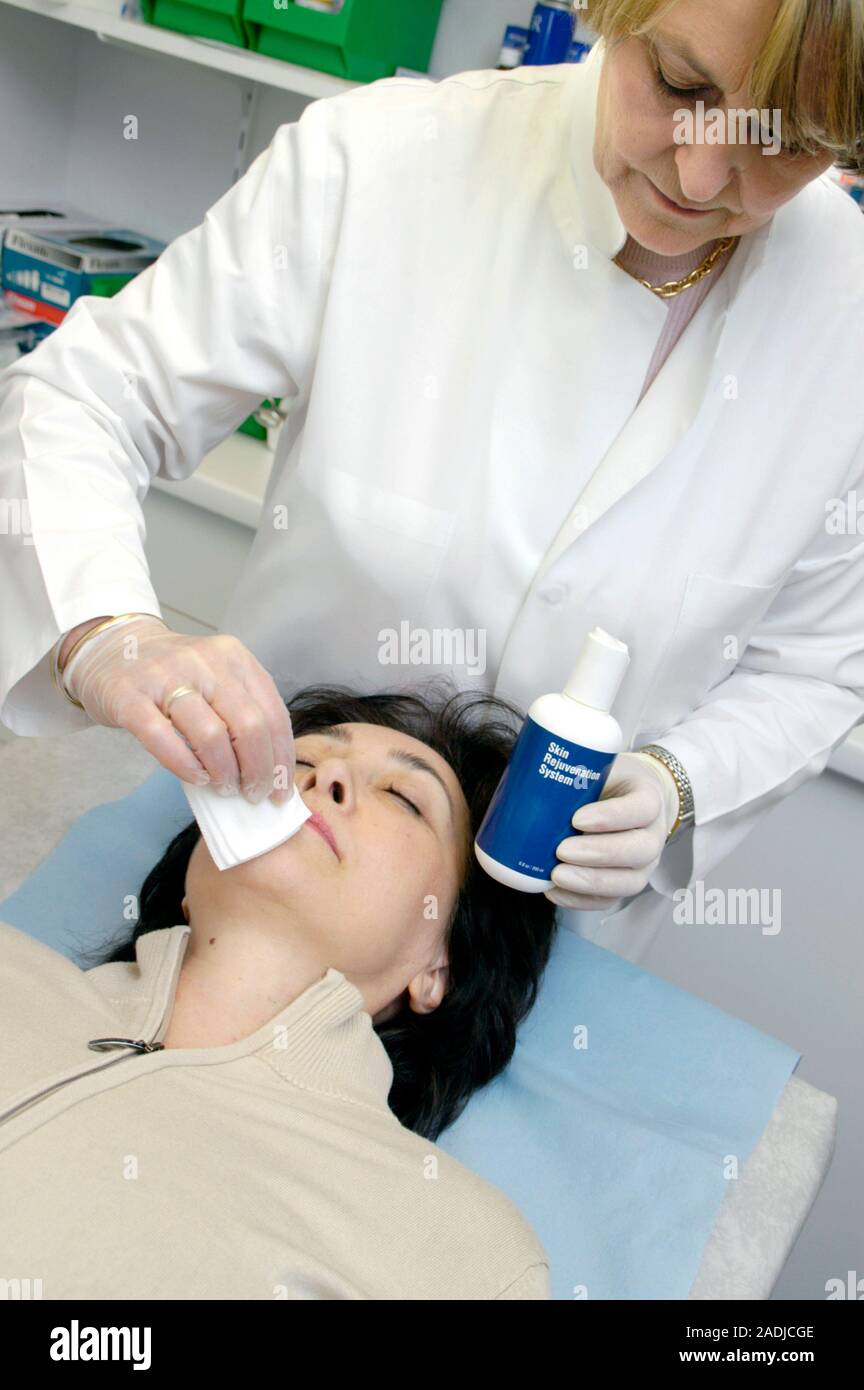 Chemical peel. Dermatologist cleaning a woman's face prior to carrying ...