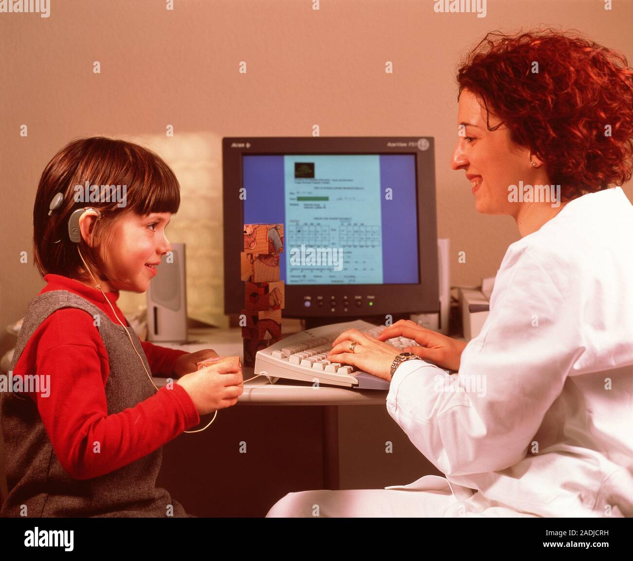 Cochlear implant testing. Audiologist testing the hearing ability of a ...