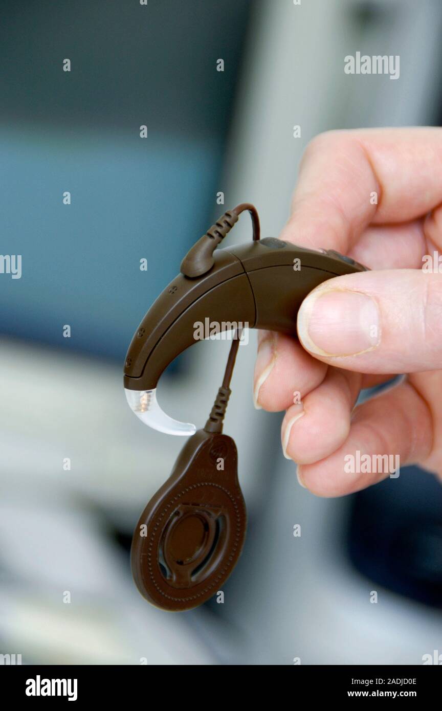 MODEL RELEASED. Cochlear implant external parts. Audiologist holding ...
