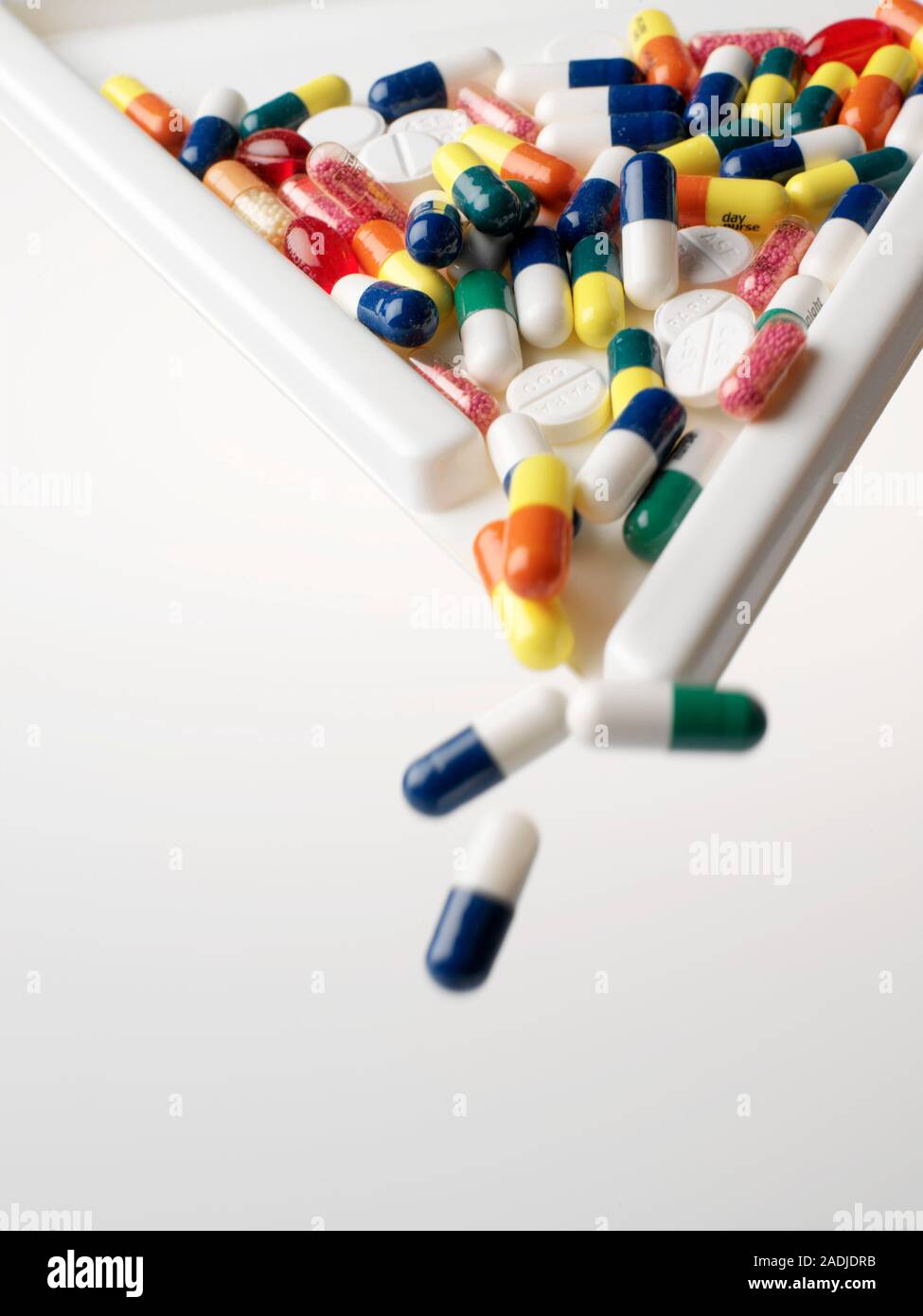 Medication. Assorted capsules and tablets spilling from a triangular ...