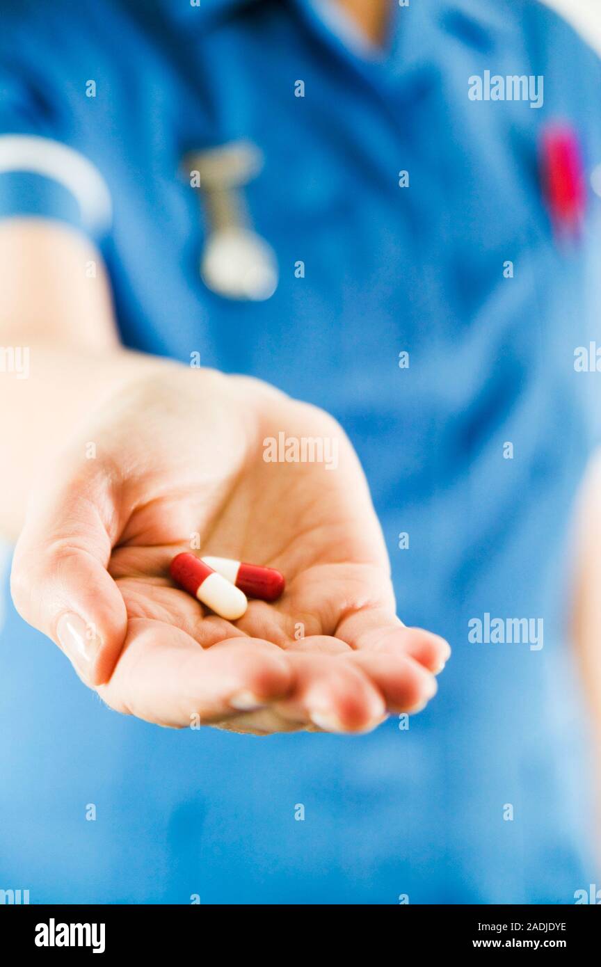 Paracetamol capsules. Nurse holding two paracetamol painkiller capsules ...