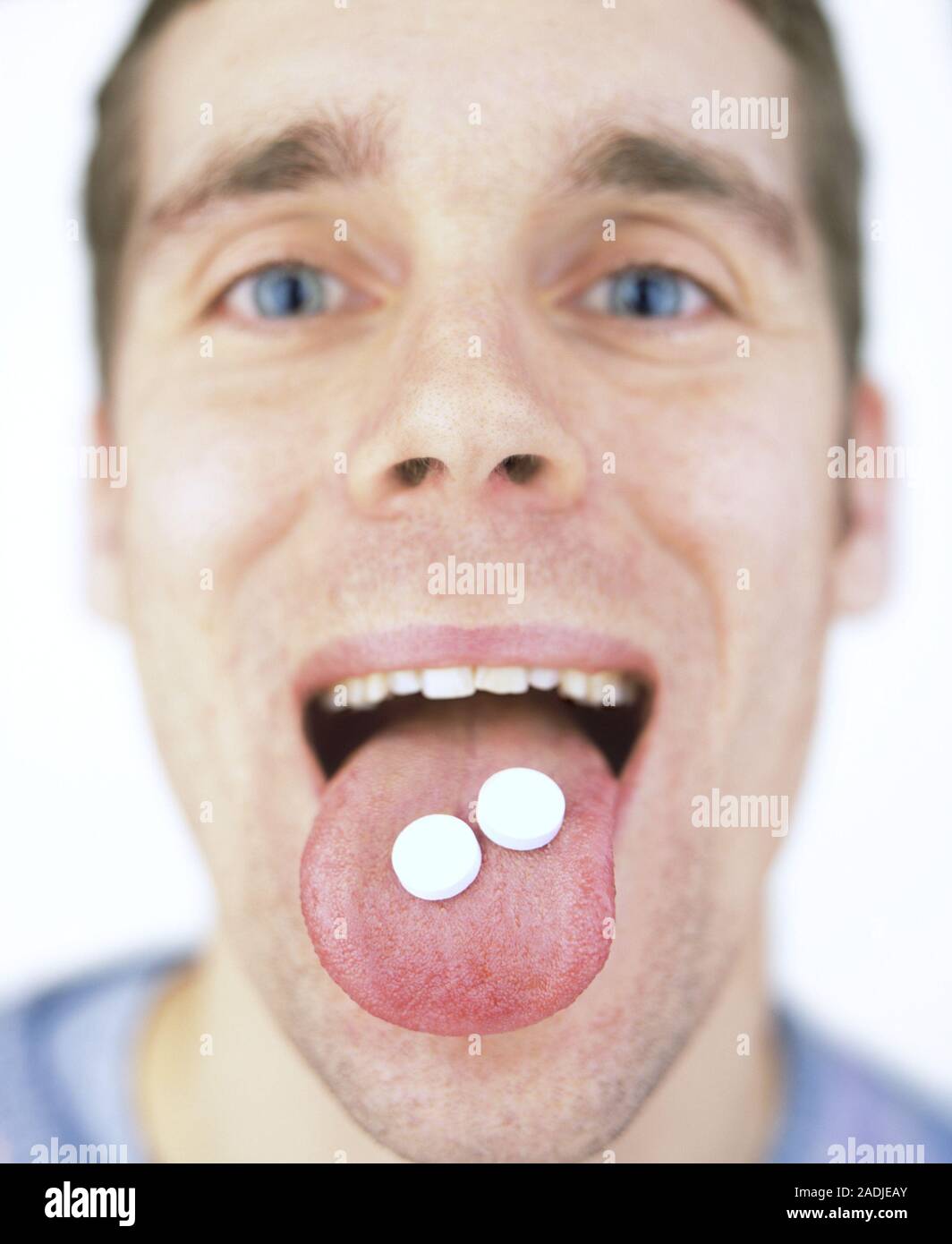 Taking tablets. Man displaying two drug tablets on his tongue Stock ...
