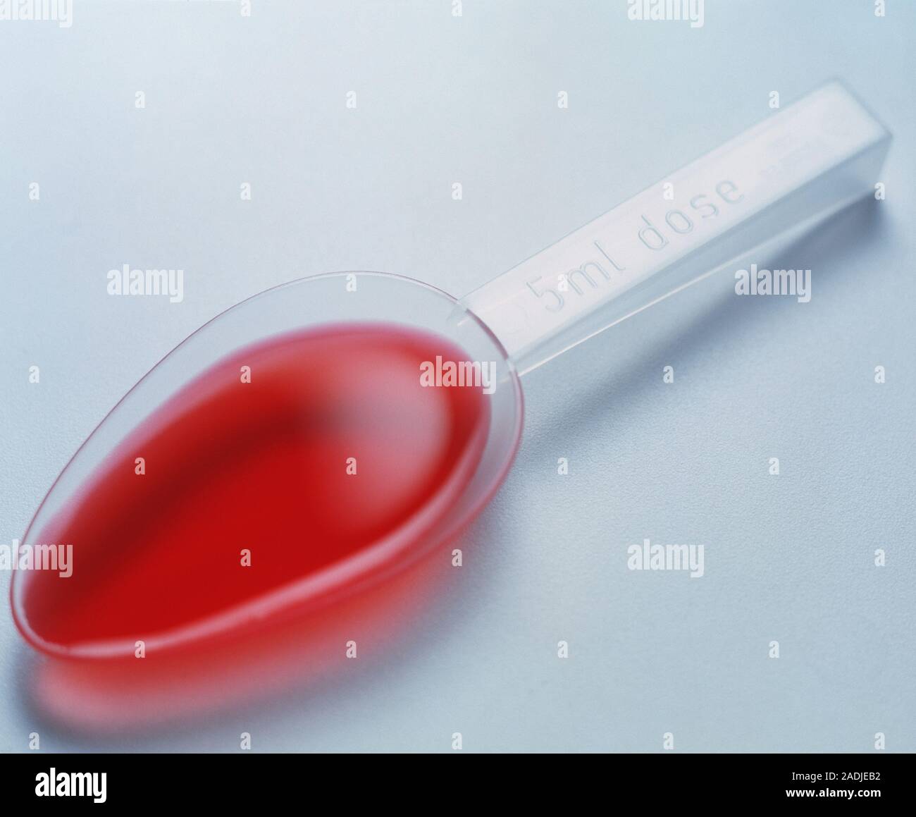 Spoonful of medicine. Red liquid medicine in a 5 millilitre spoon which ...